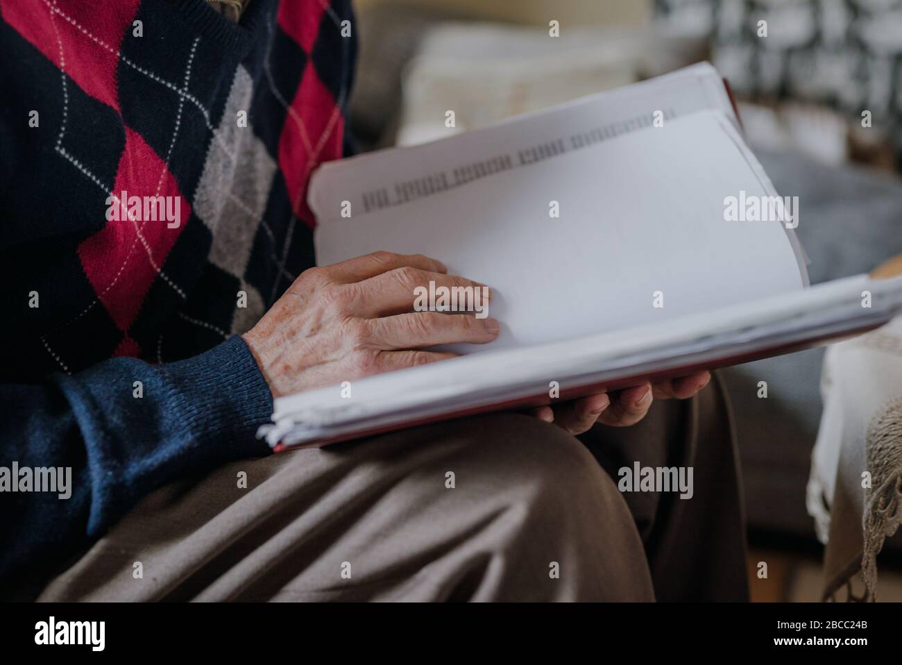 Old man reading book sitting on couch Stock Photo - Alamy