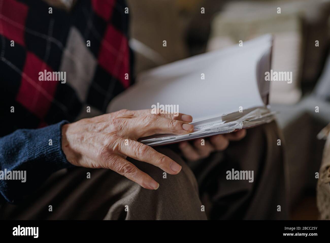 Old man reading book sitting on couch Stock Photo - Alamy