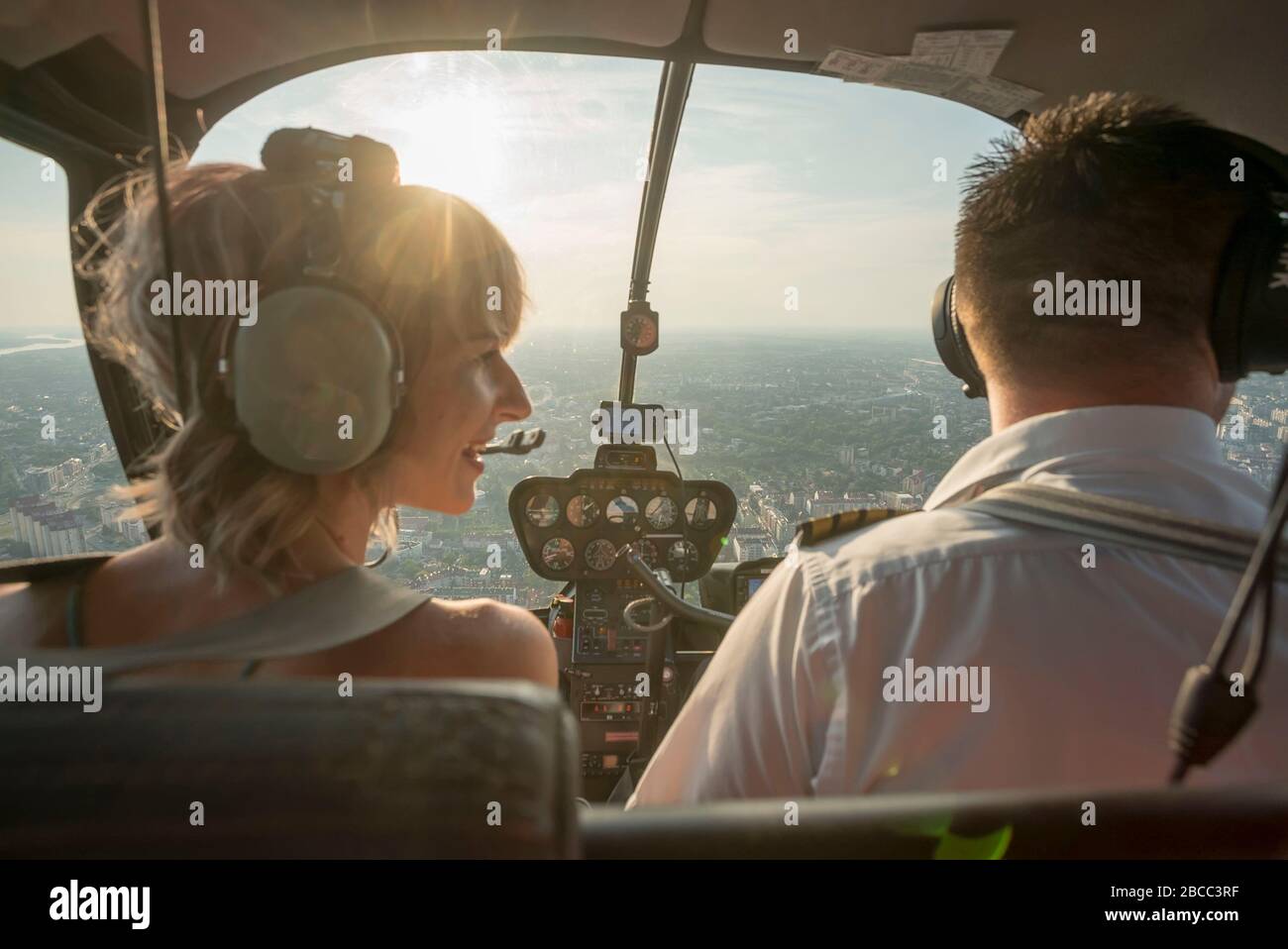 Portrait of beautiful blonde women and pilot enjoying helicopter flight ...