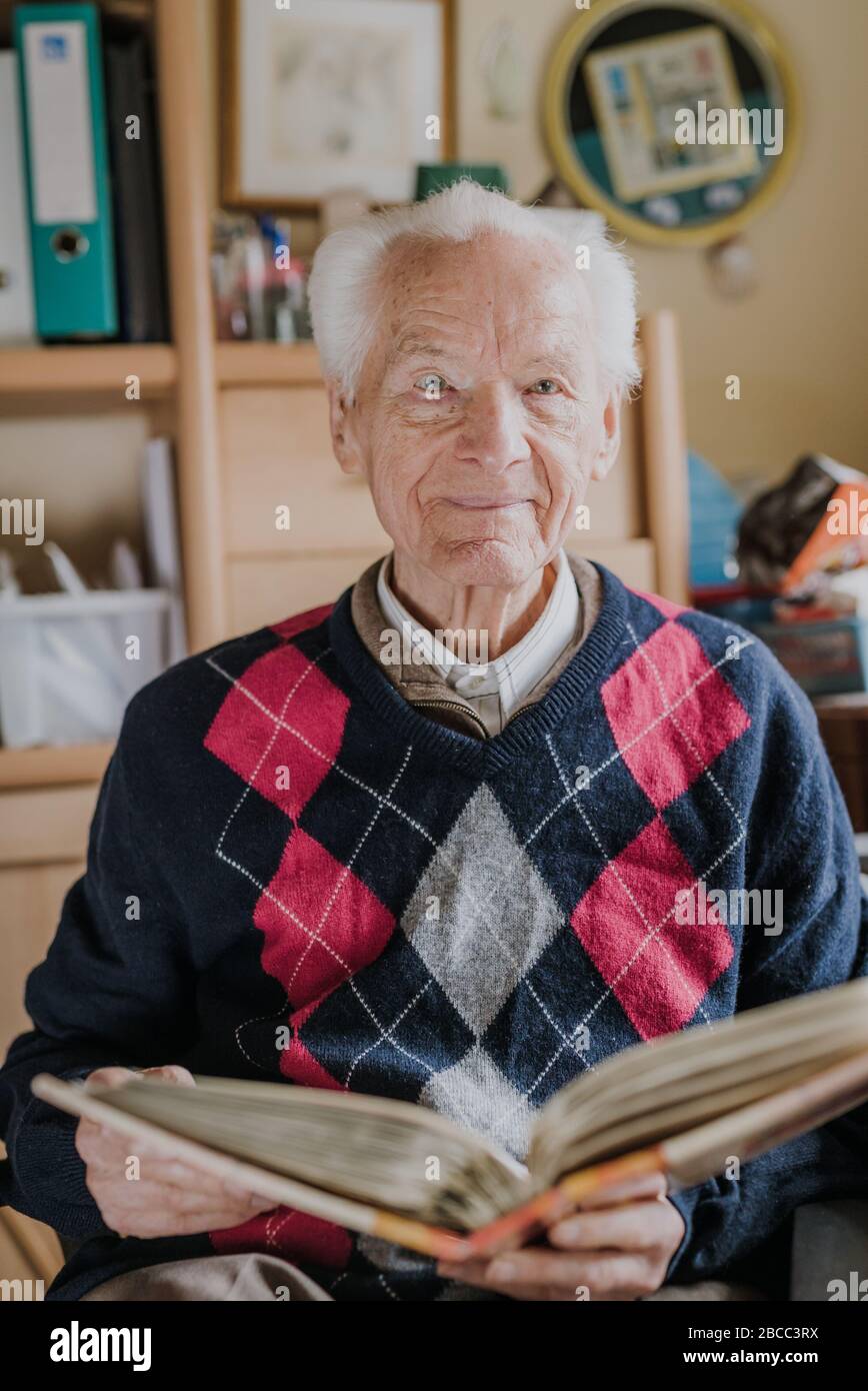 Grandfather looking at old albums with family photos. Retirement and ...