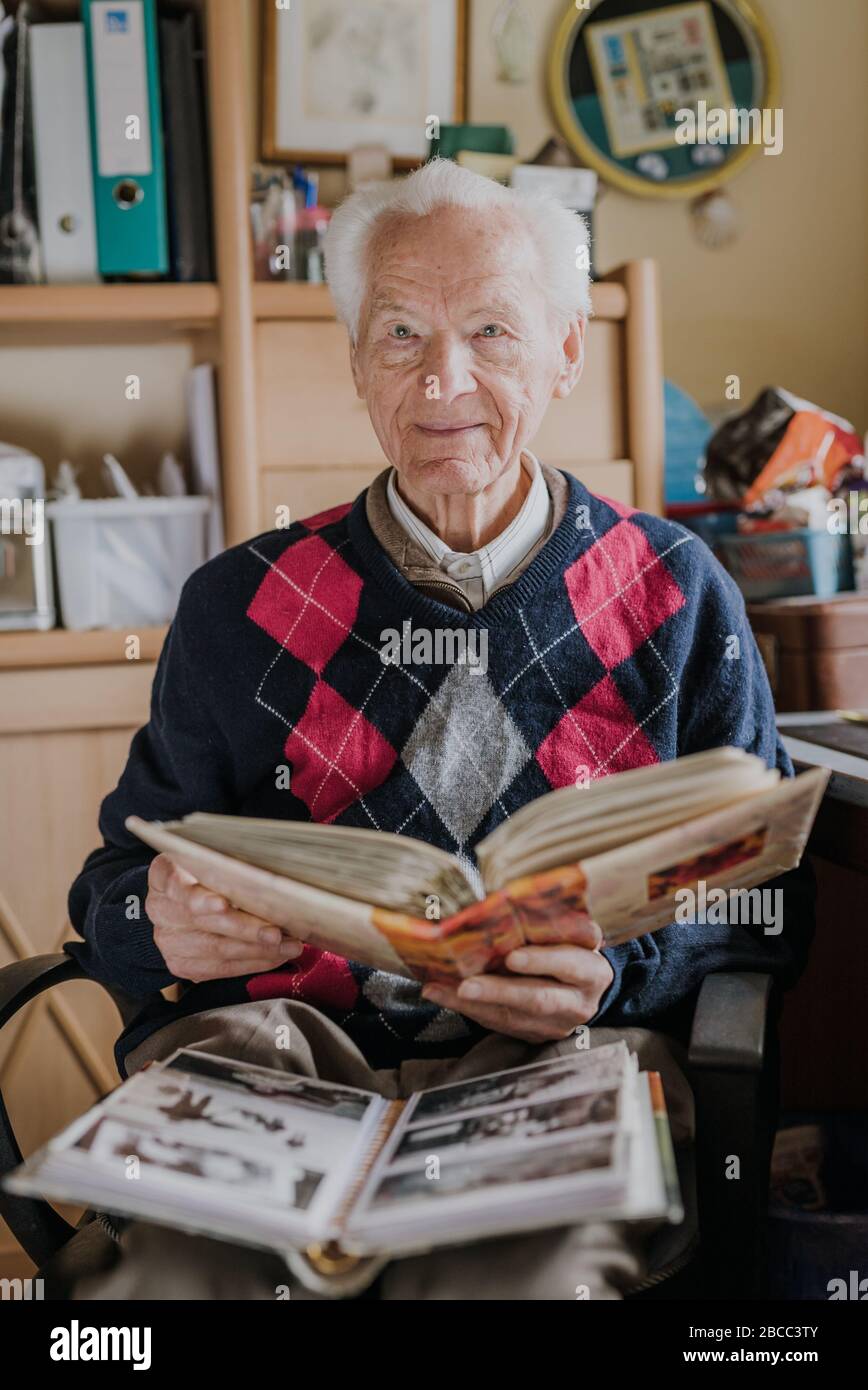 Grandfather looking at old albums with family photos. Retirement and ...