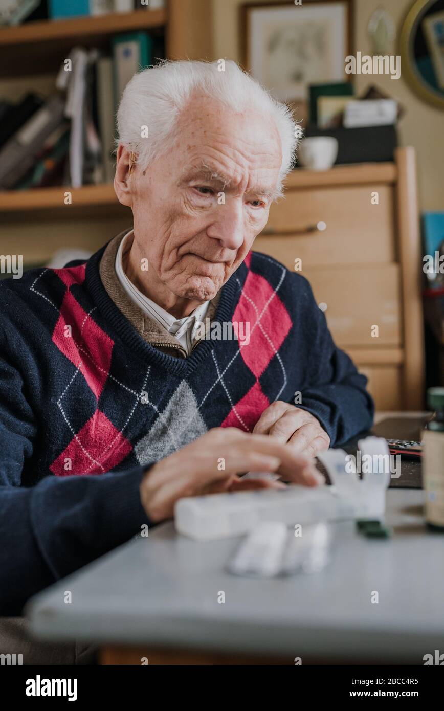 Old man puts tablets in box, organizes medicines for each day of week ...