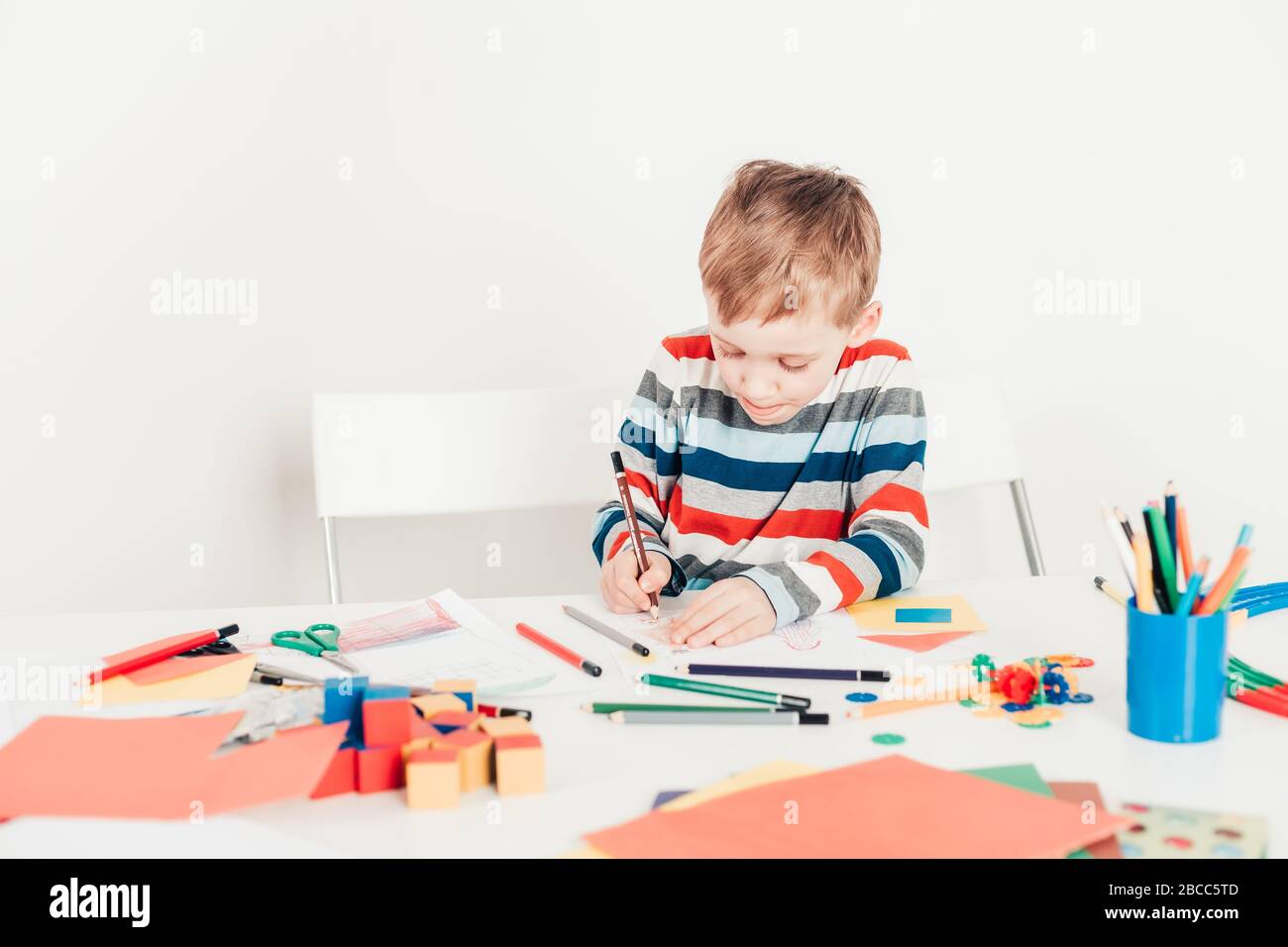 Cute child study drawing at the table, colored pencils and paper around ...