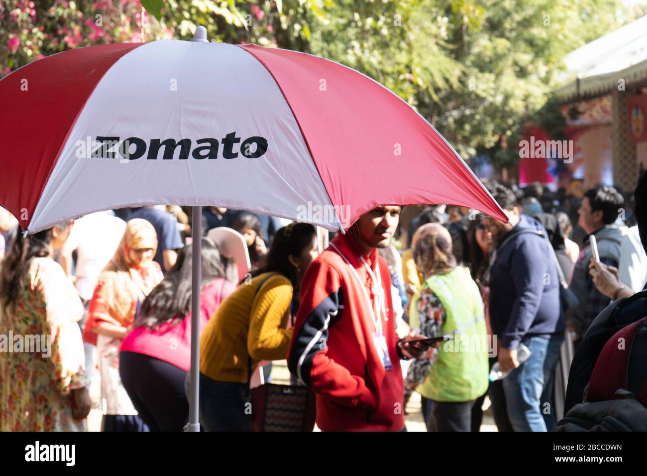Umbrerlla with Zomato brand name and colors with out of focus crowd ...