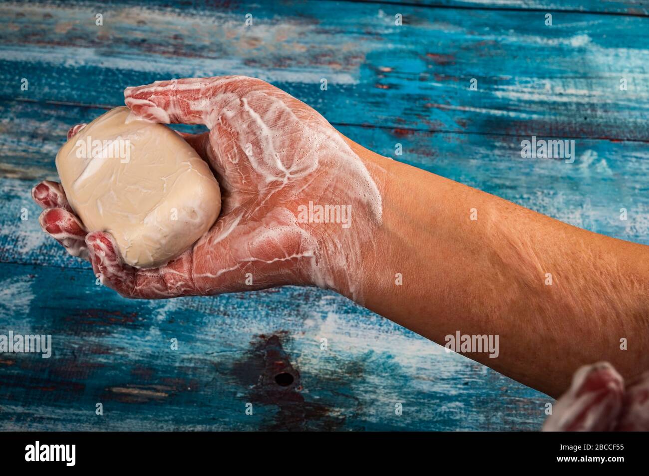 Someone is holding a piece of toilet soap on a wooden background in a ...
