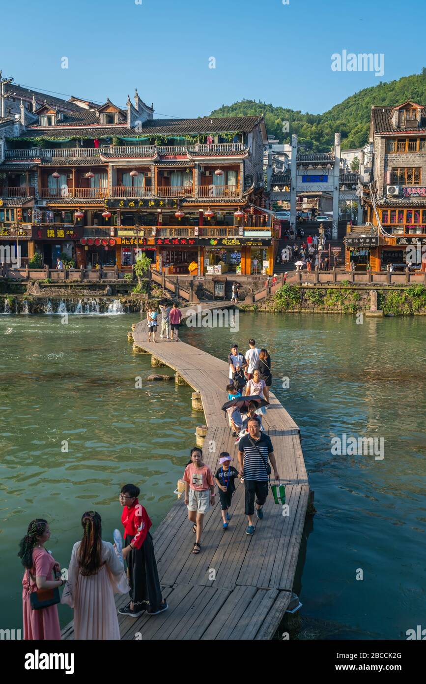 Feng Huang, China - August 2019 : People crossing water on the wooden ...