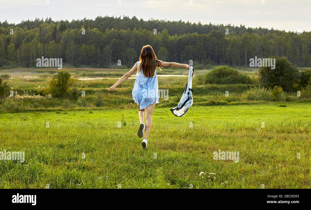 Beautiful woman runnig into the wild nature and waving her sacrf ...