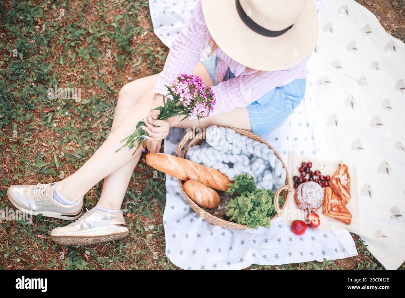 beautiful relaxed girl in a straw hat in nature picnic basket of flowers in the rays of the soft ...