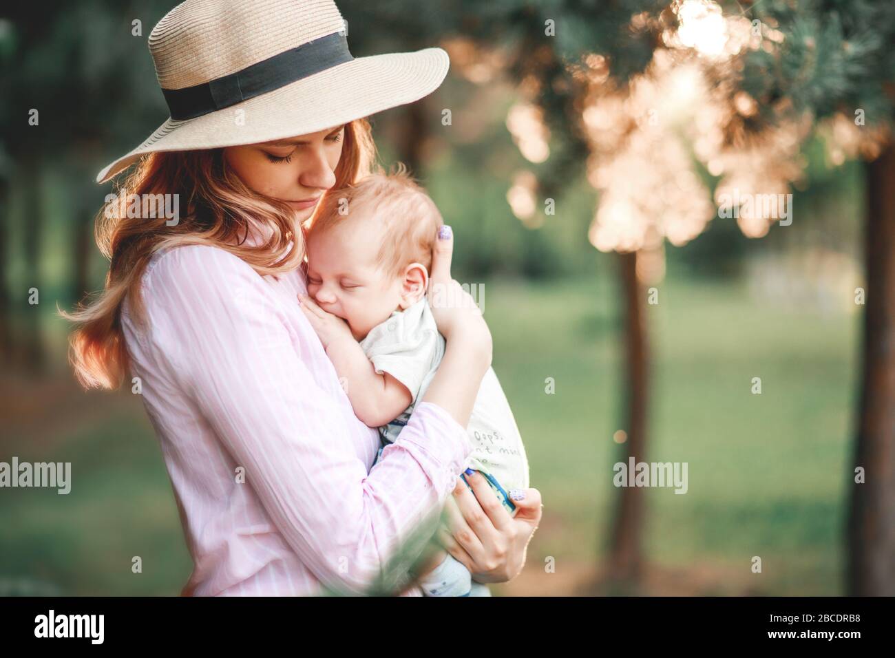 A mother hugs her child outdoors in nature against the backdrop of the ...