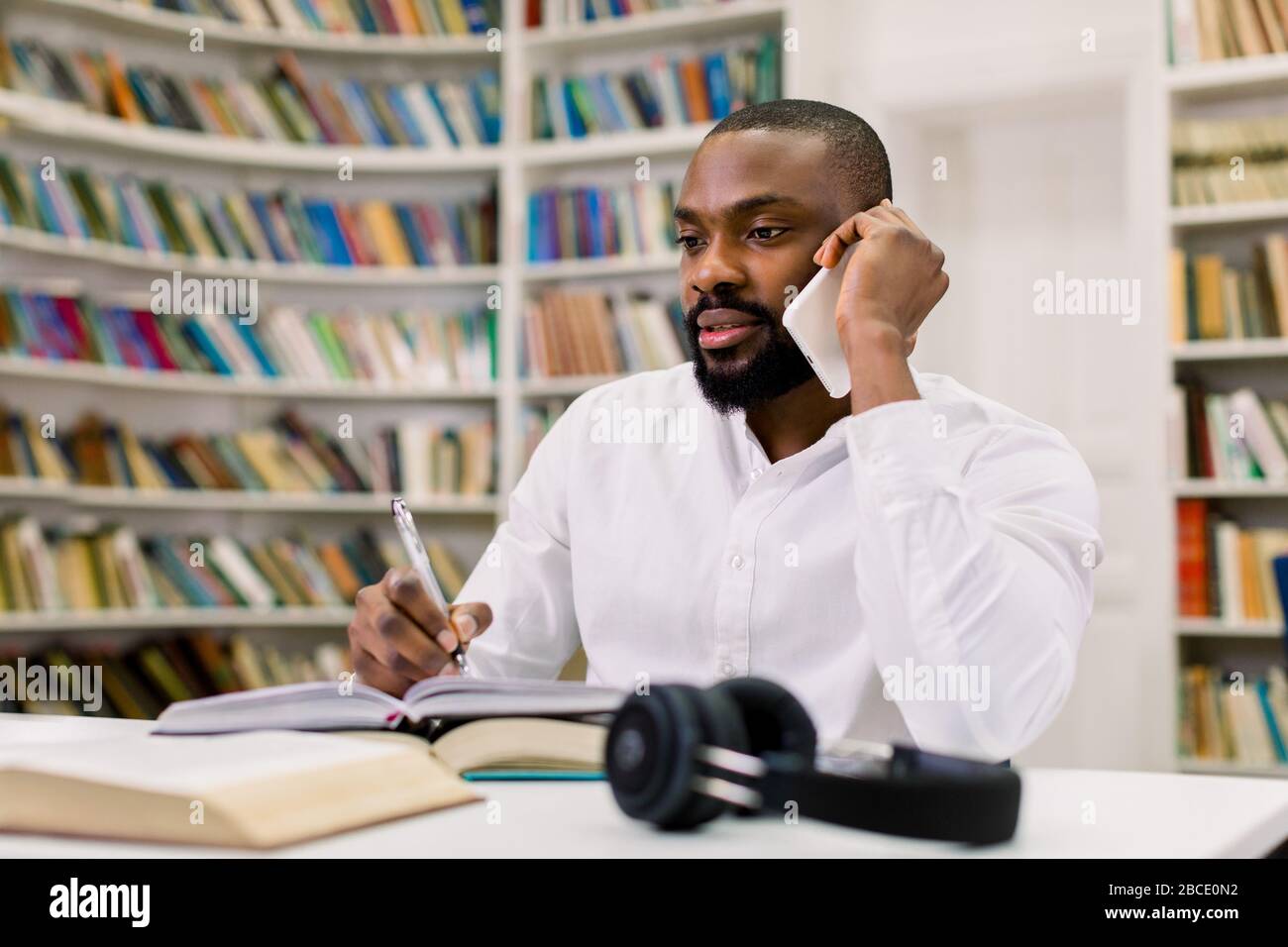 Male African student studying in college library, sitting at the table ...
