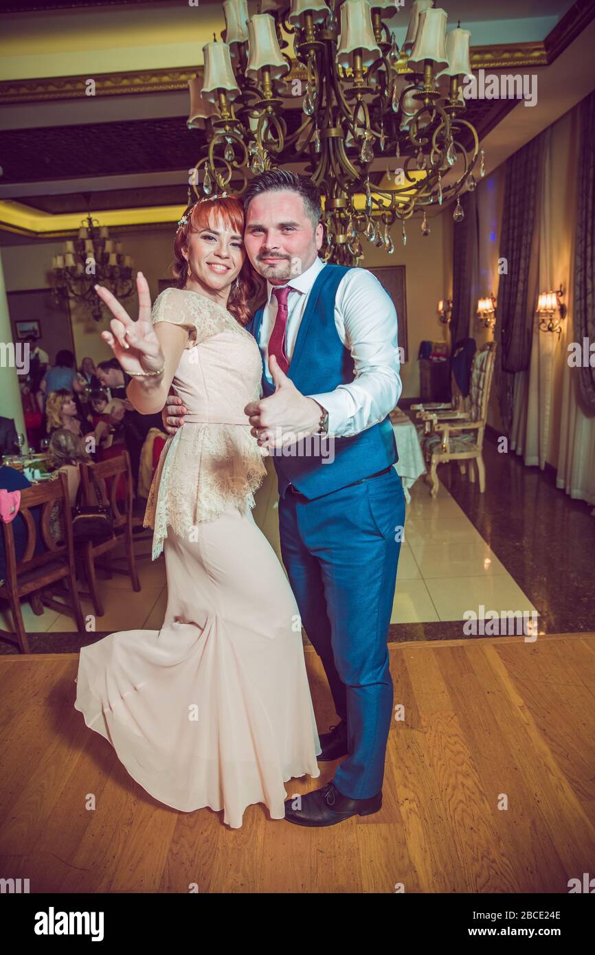 Groom holds bride's hand dancing with her in the middle of a restaurant ...