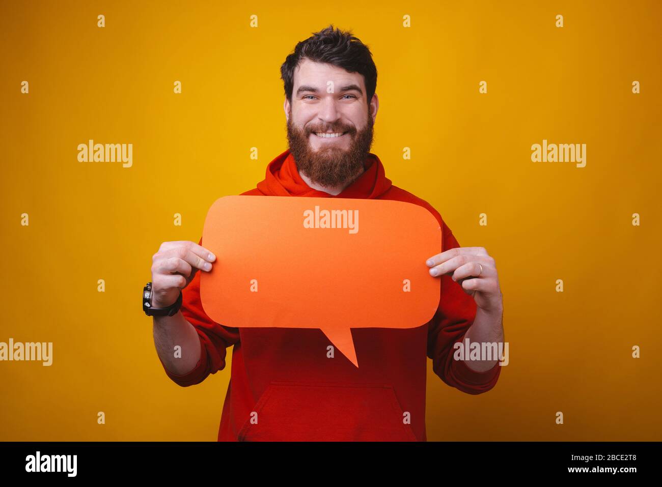 Smiling young bearded man is holding a bubble speech in front of his ...