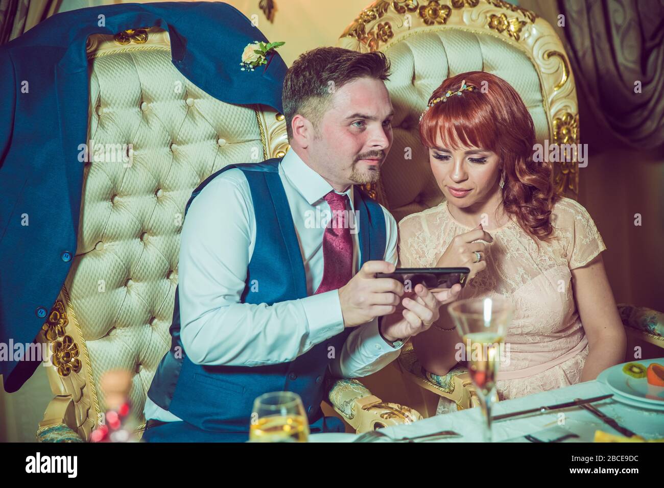 A bride and groom using a mobile phone . Close-up of beautiful bride ...