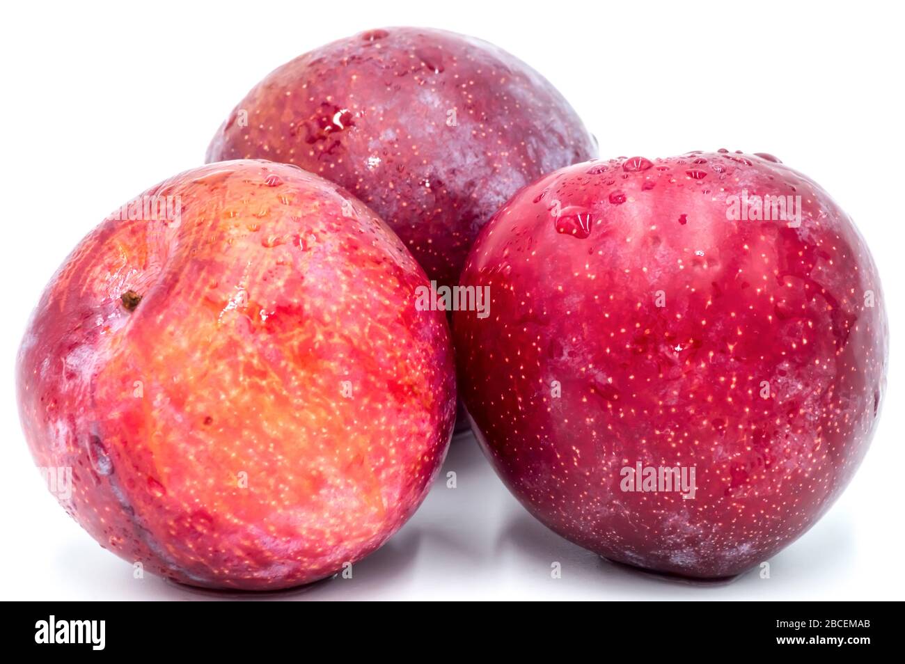 Three ripe red round plums isolated on white. Big plan Stock Photo - Alamy