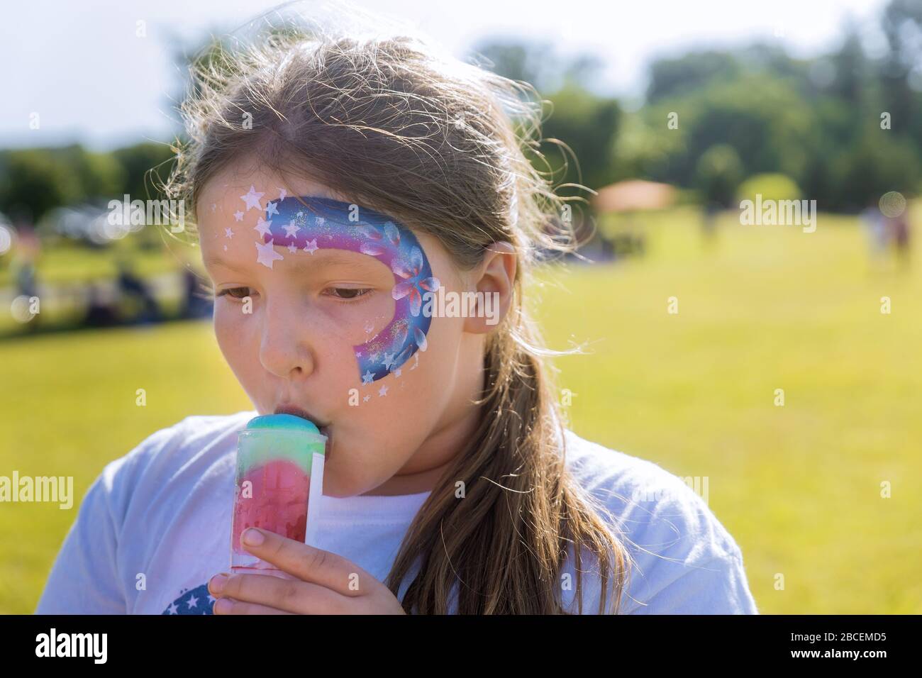 Teenager with face paint eating rainbowl color ice cream Stock Photo ...
