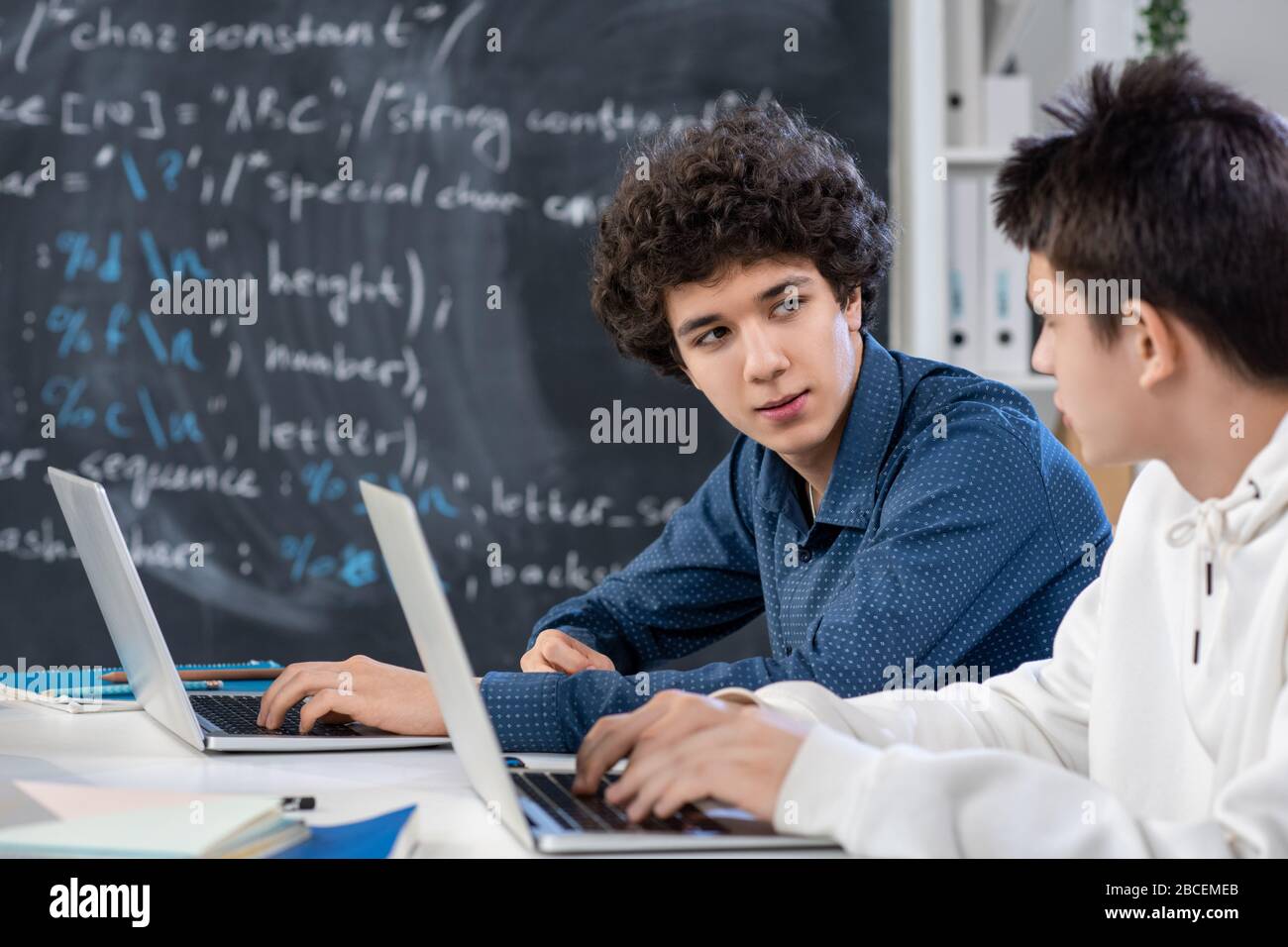 One of guys looking at his classmate during individual work while ...