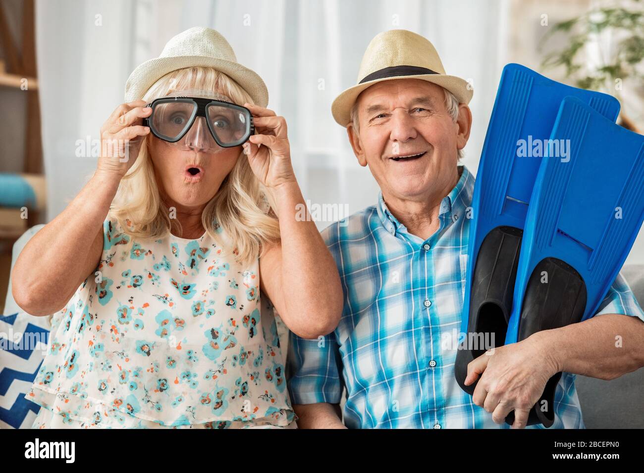 Senior couple sitting in travel agency sitting wearing hats and ...