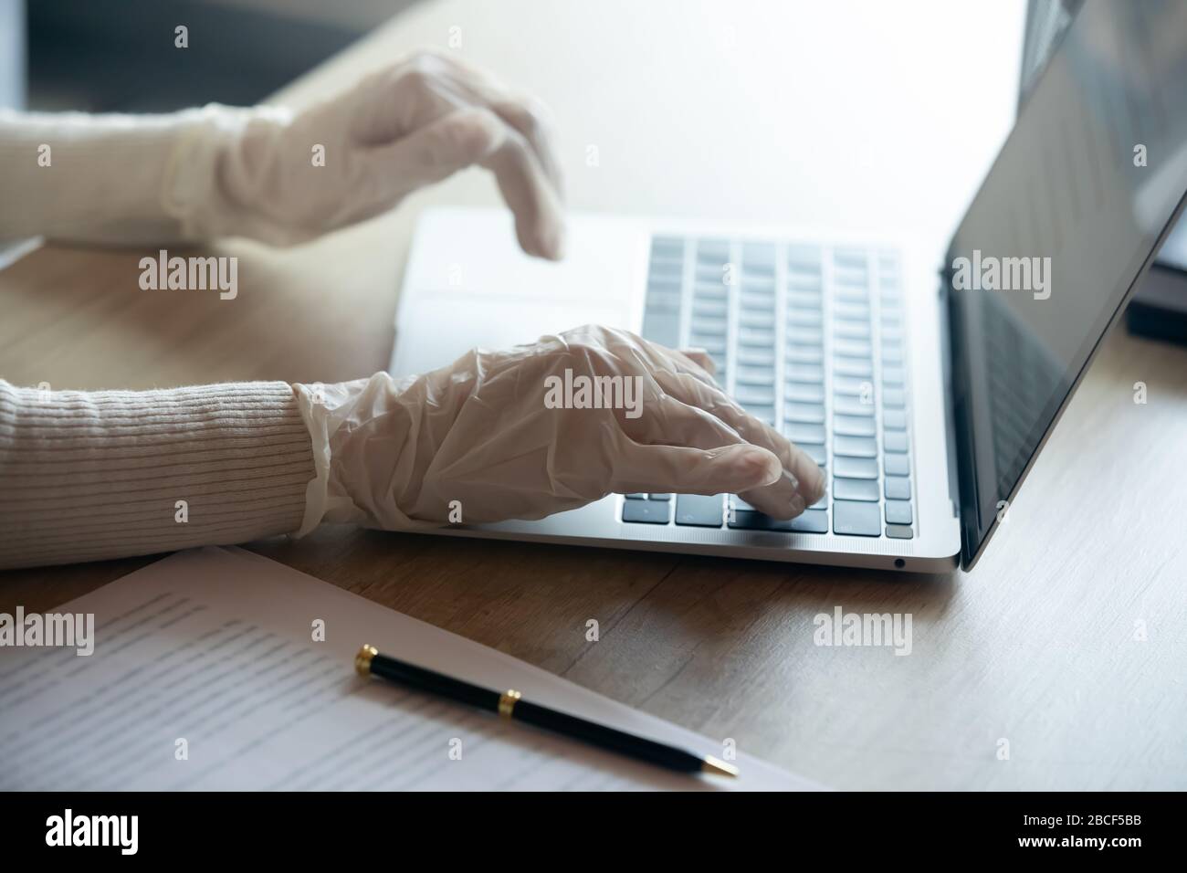 Young cautious businesswoman working on computer in gloves Stock Photo ...