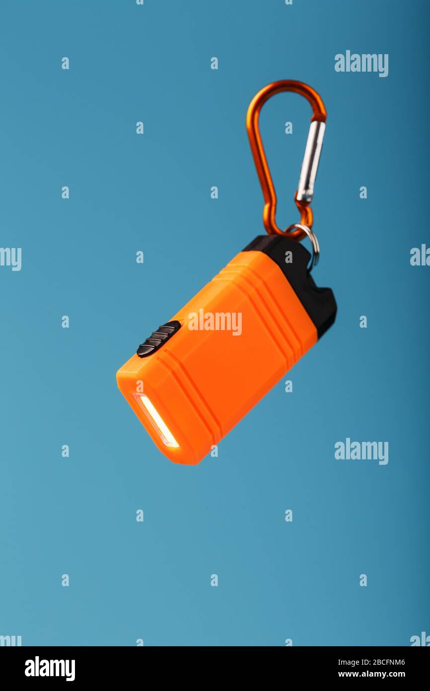 Orange led Flashlight with a carabiner on a blue background. LED lights ...