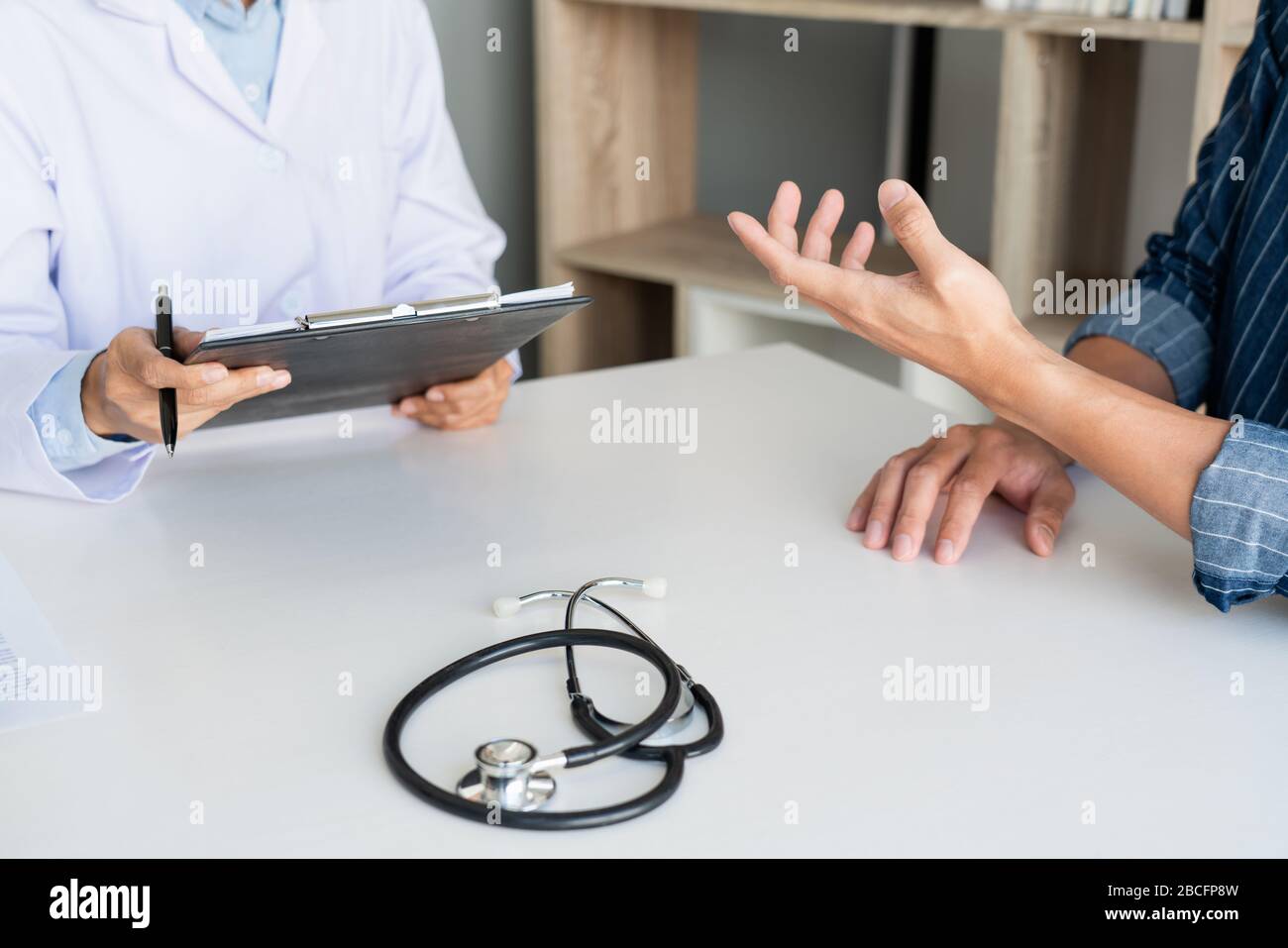 doctor working with patient taking notes with clipboard and discussing ...