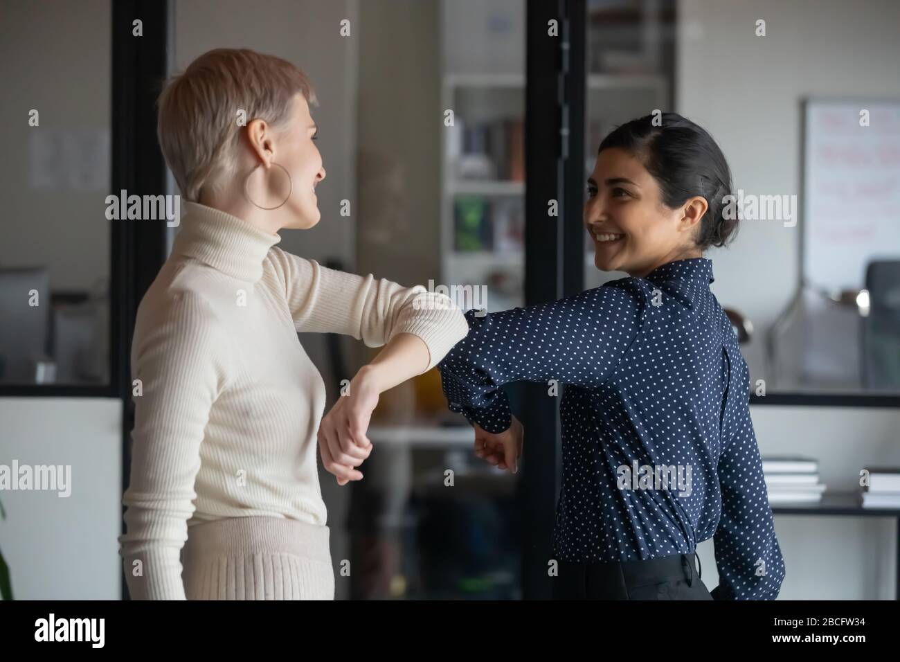Friendly smiling millennial diverse female colleagues keeping social ...