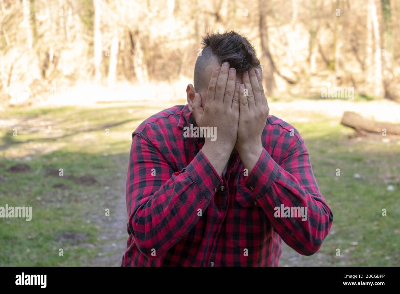 Man crying in nature. Person in agony holding hands on his face ...