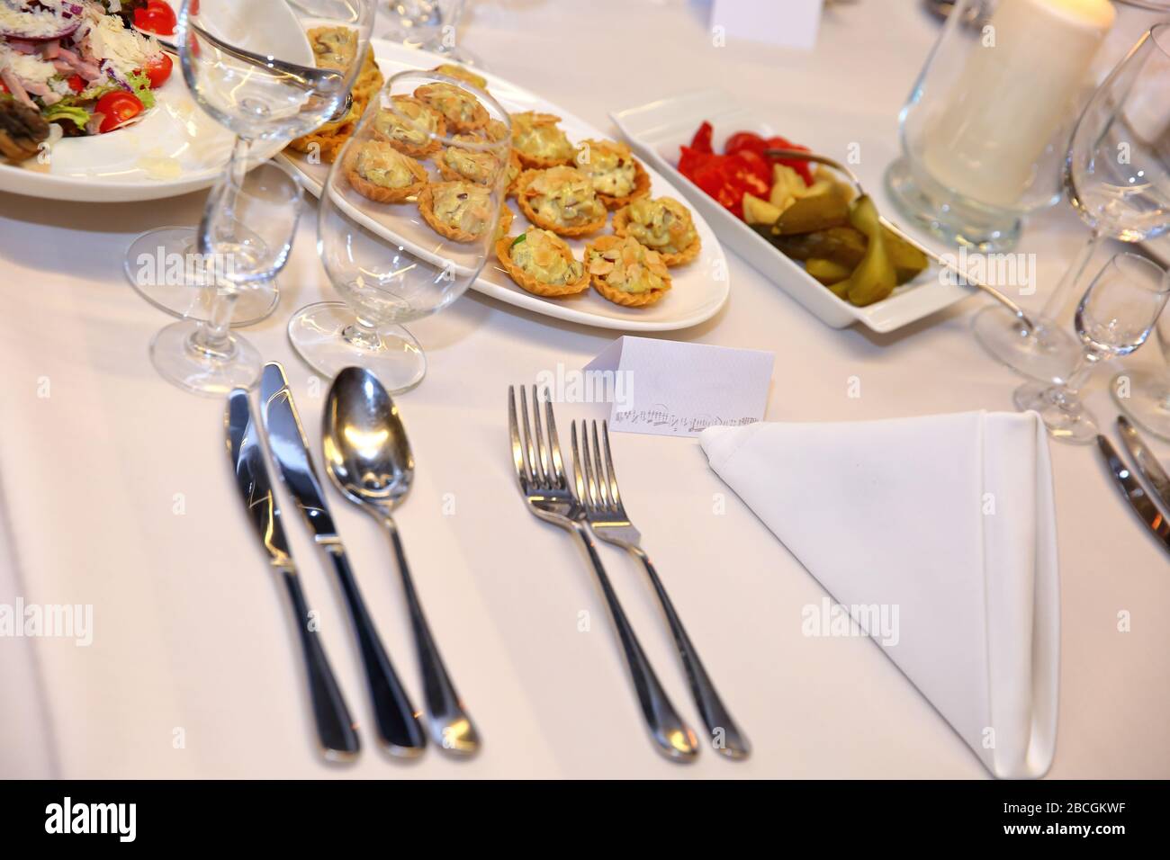 A huge table, covered with a white tablecloth with all the cutlery and ...