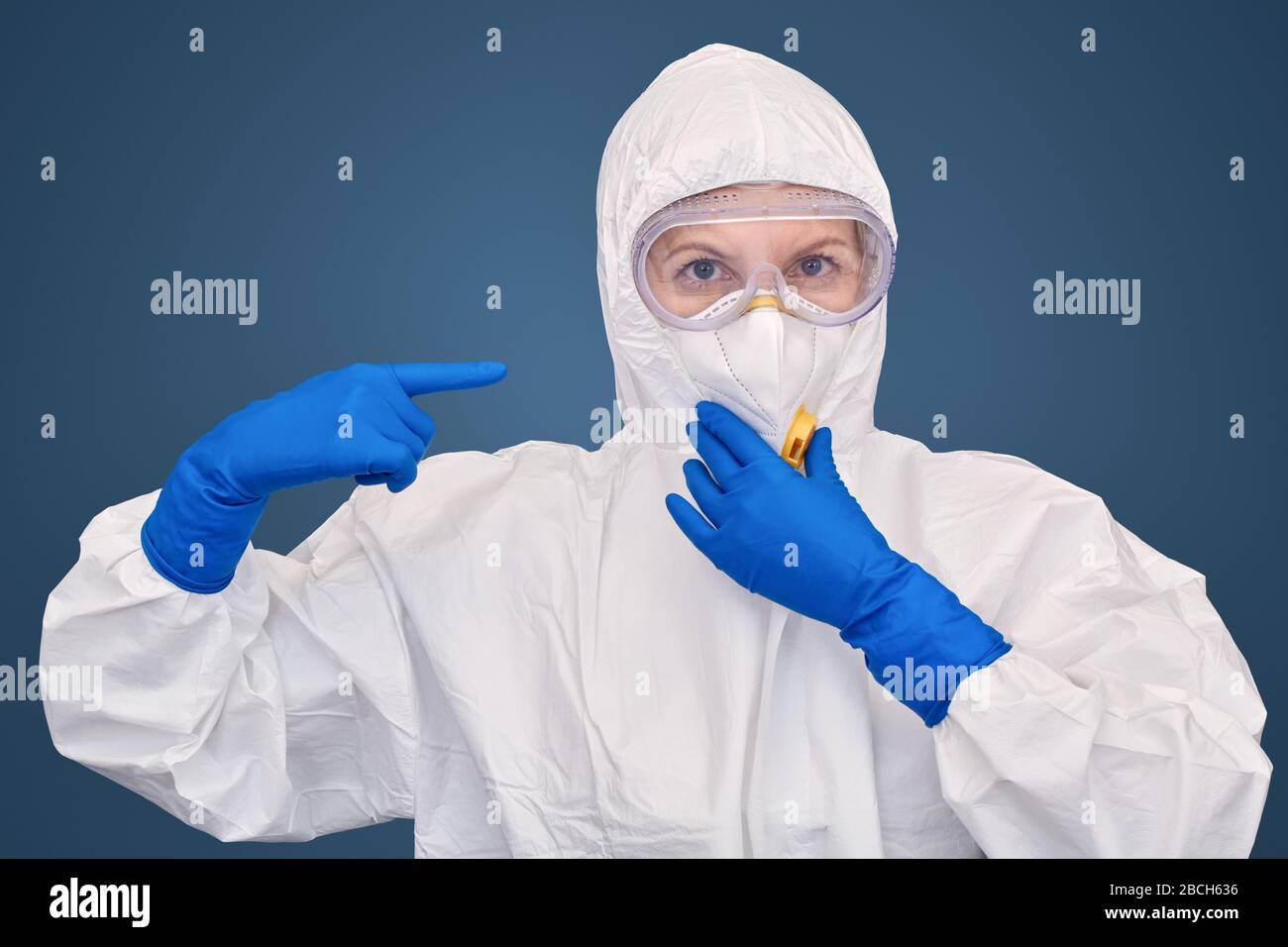Woman doctor in white hazmat suit pointing at respirator Stock Photo ...
