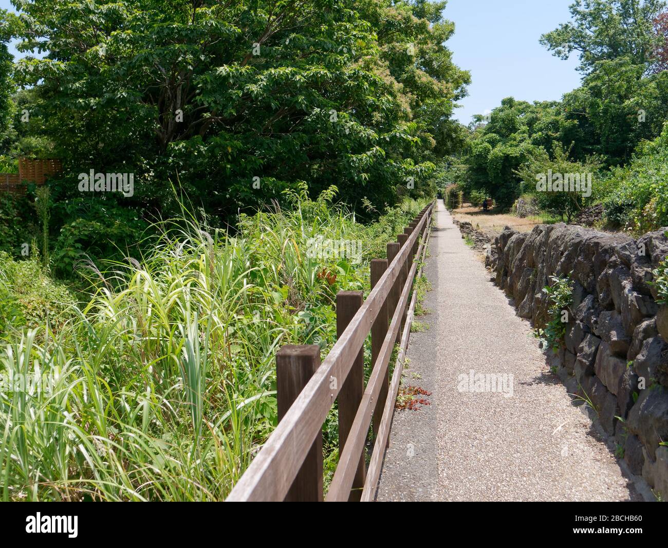 Long footpath with wooden fence next to the Tajima river leading to the ...