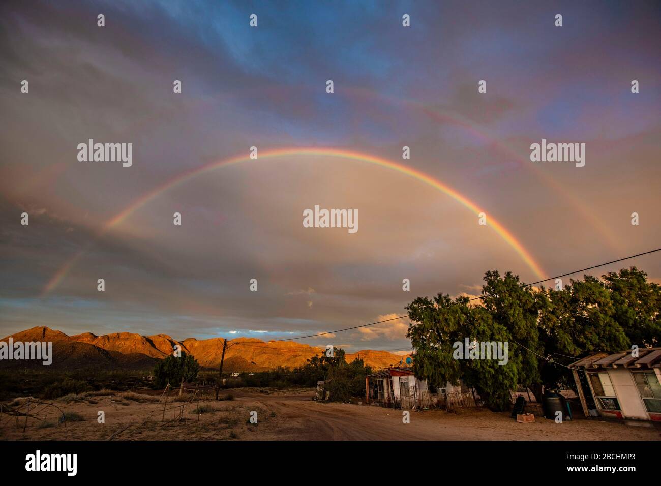rainbow at sunset over the hills and the town or community of Punta ...