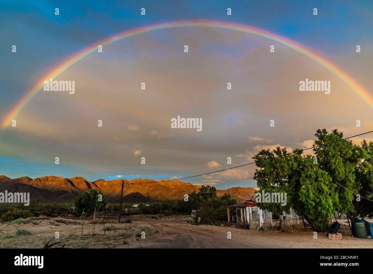 rainbow at sunset over the hills and the town or community of Punta ...