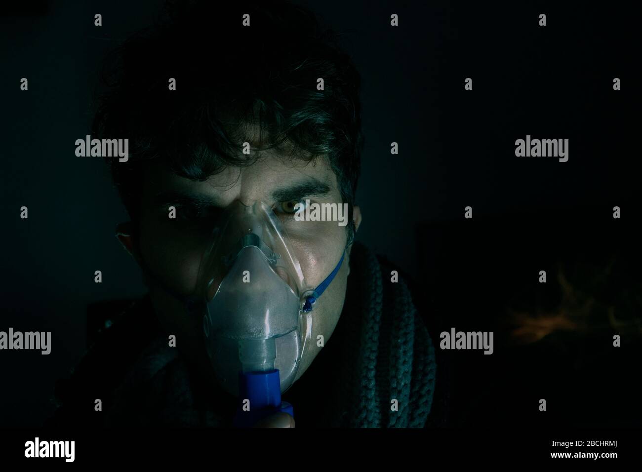 Dark Portrait of man using steam vapor inhaler nebulizer doing aerosol ...