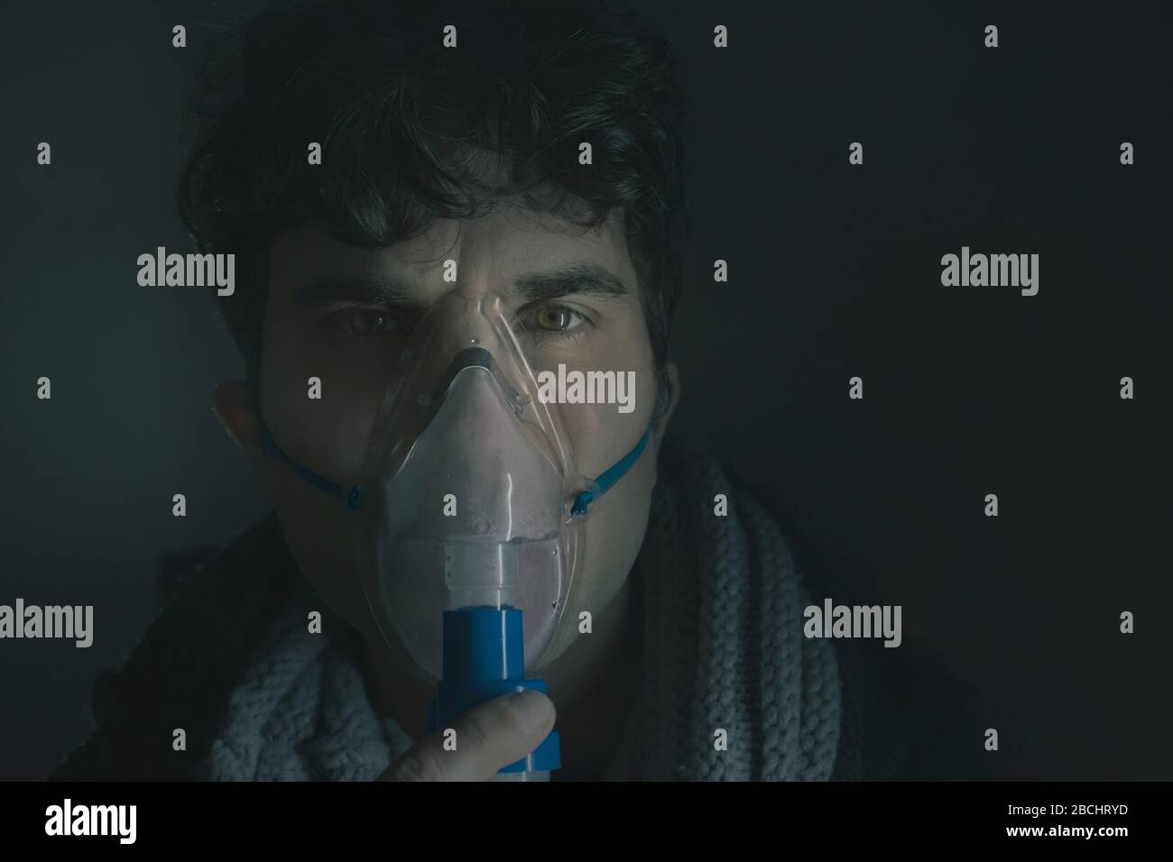 Dark Portrait of man using steam vapor inhaler nebulizer doing aerosol ...