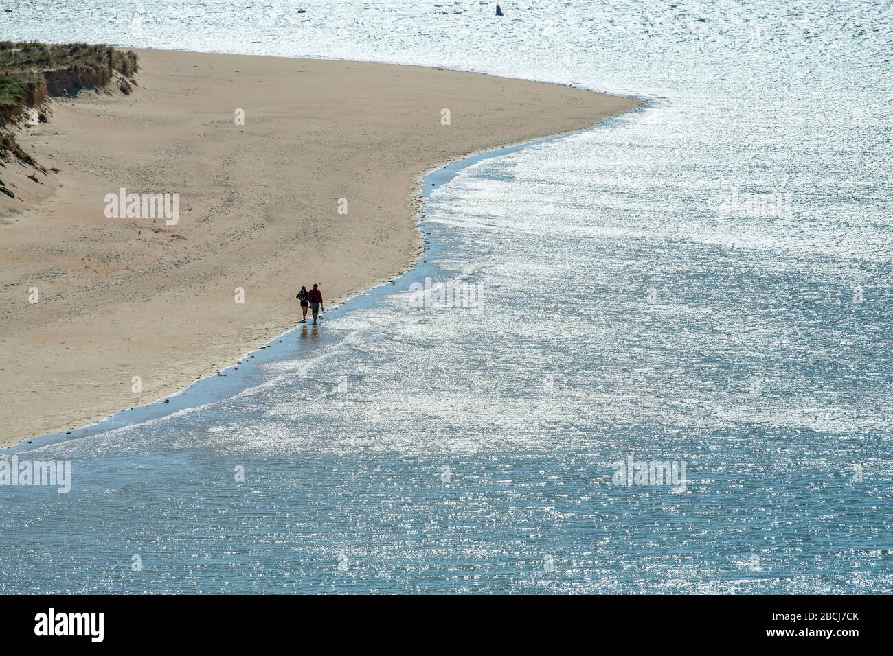A couple walk along the deserted Brae Hill beach in the Camel Estuary ...