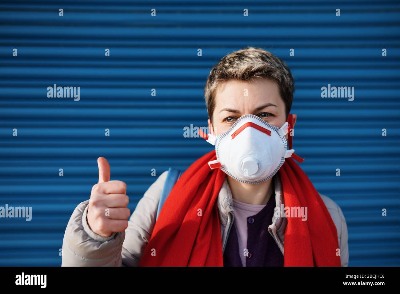 Portrait of Woman wearing a white and red face mask, grey jacket and ...