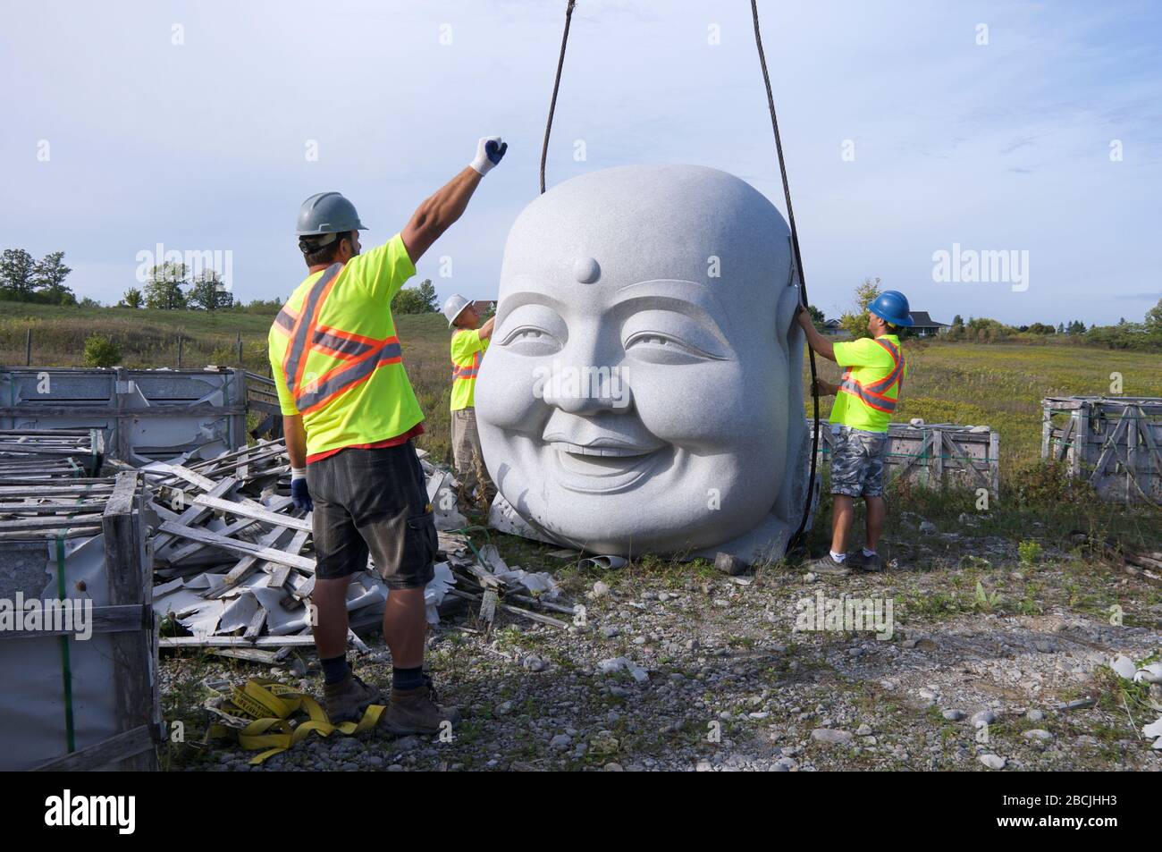 Using hand signals in the lift up of the stone statue by crane truck in ...