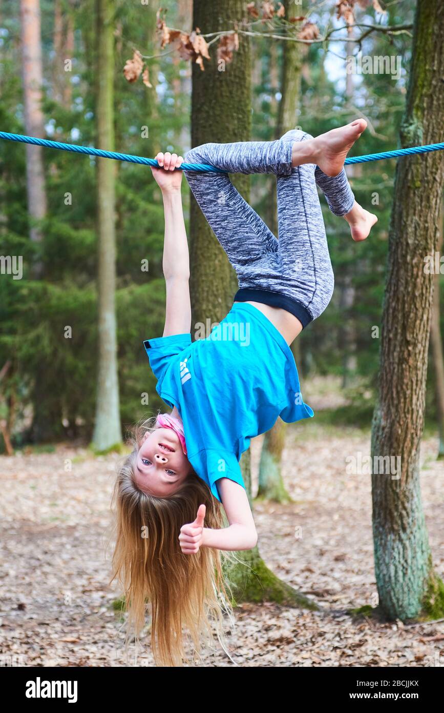 Young child girl hanging on rope upside down on playground in park Stock Photo - Alamy