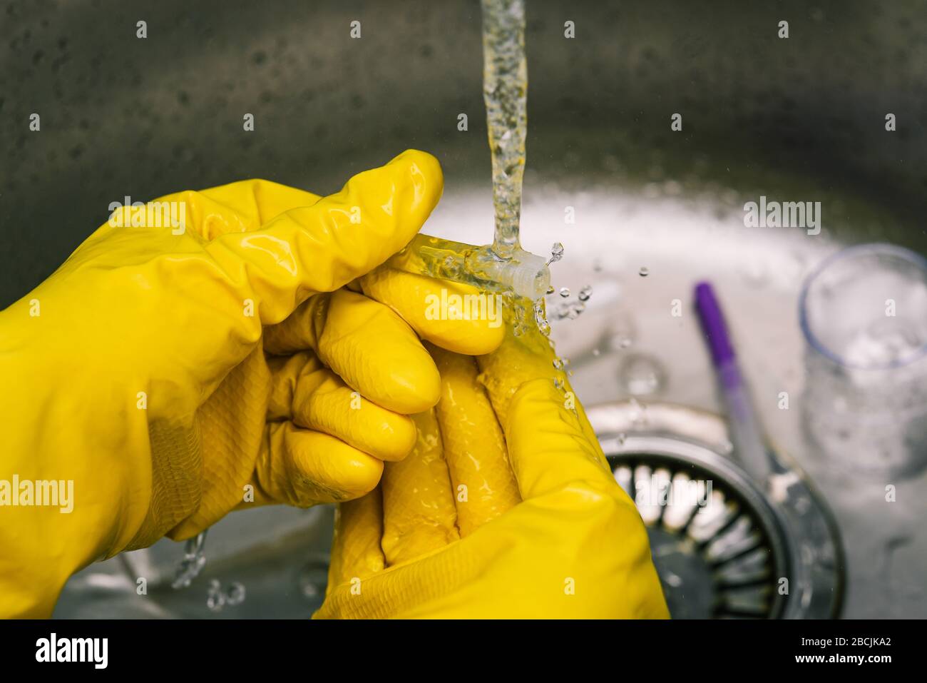 Medical worker washes test tubes under a tap with water. A scientist's ...