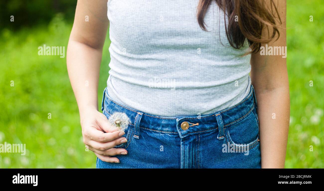 Moody picture of a dandelion flower in a jeans pocket on green ...