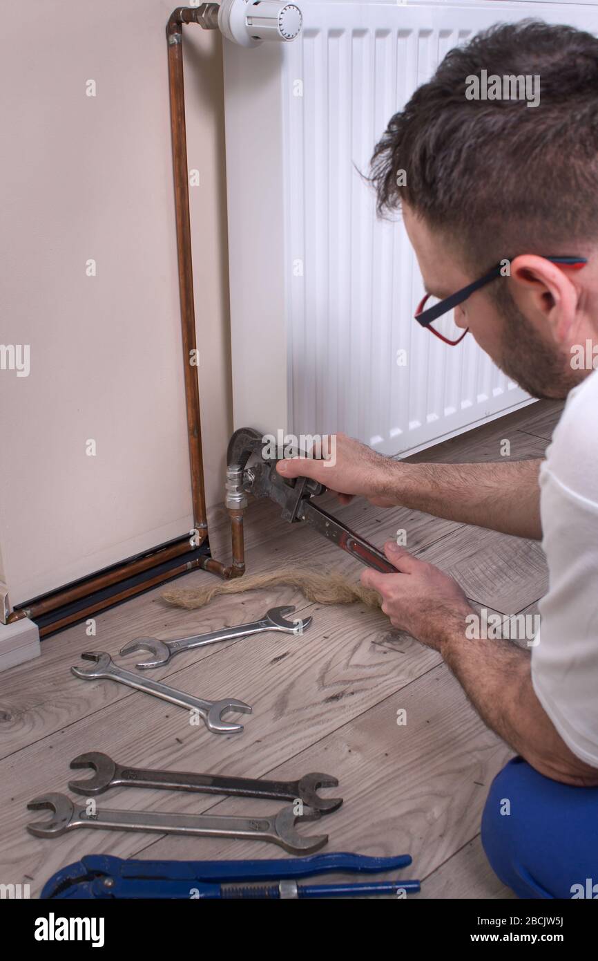 Plumber holds the adjustable wrench and adjusts the tool spacing ...