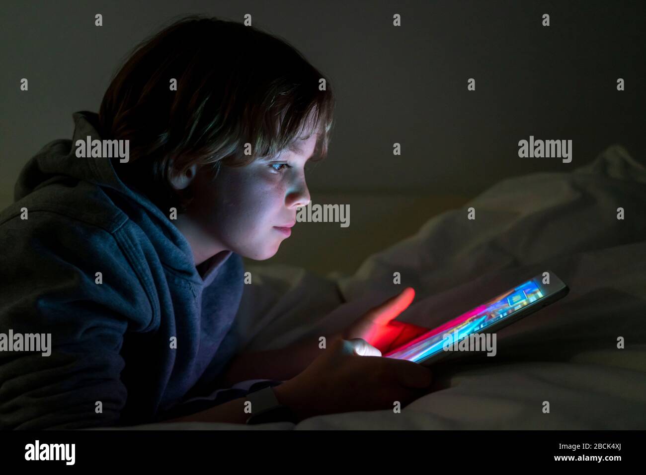 A boy plays computer games on a tablet PC, in his Children's room, on ...