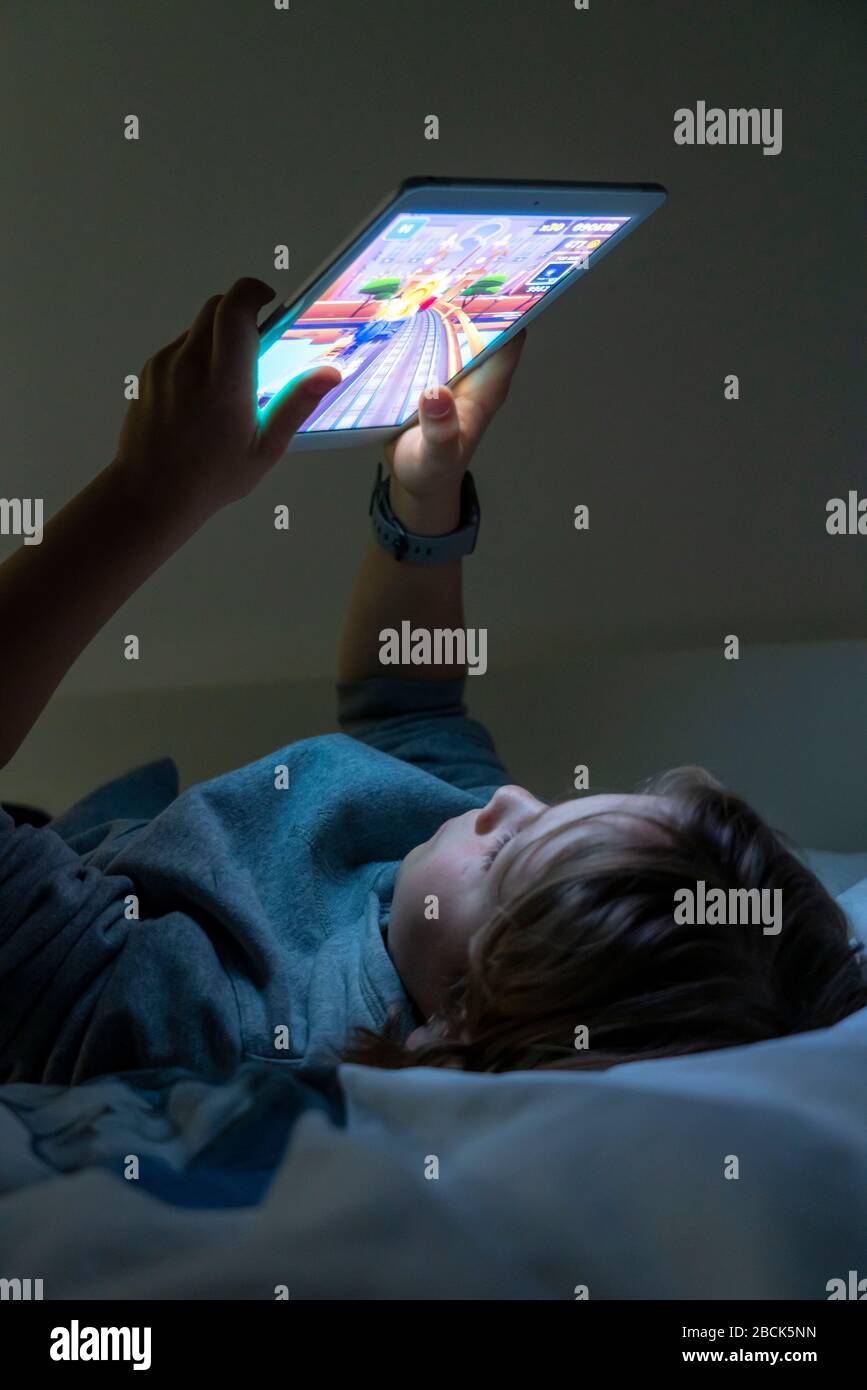 A boy plays computer games on a tablet PC, in his Children's room, on ...