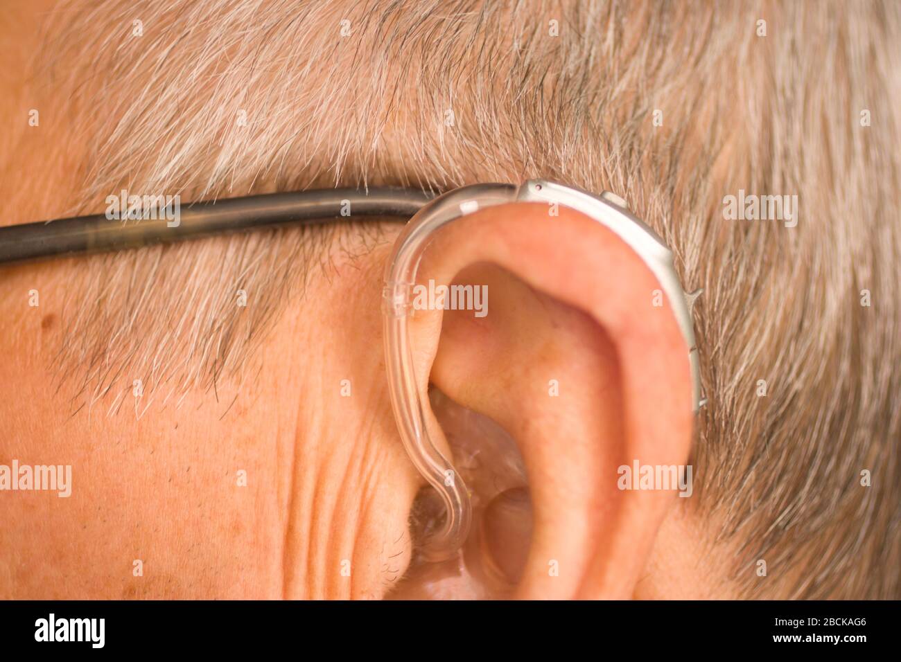Caucasian white old aged man wearing modern digital hearing aid in ear ...