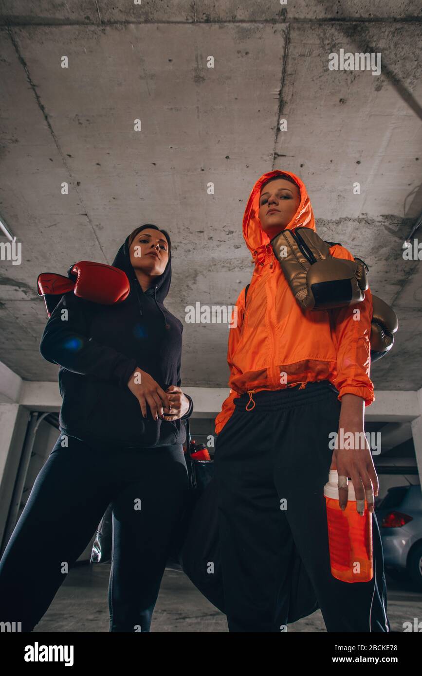 Two female boxer friends standing in a garage with boxing equipment ...