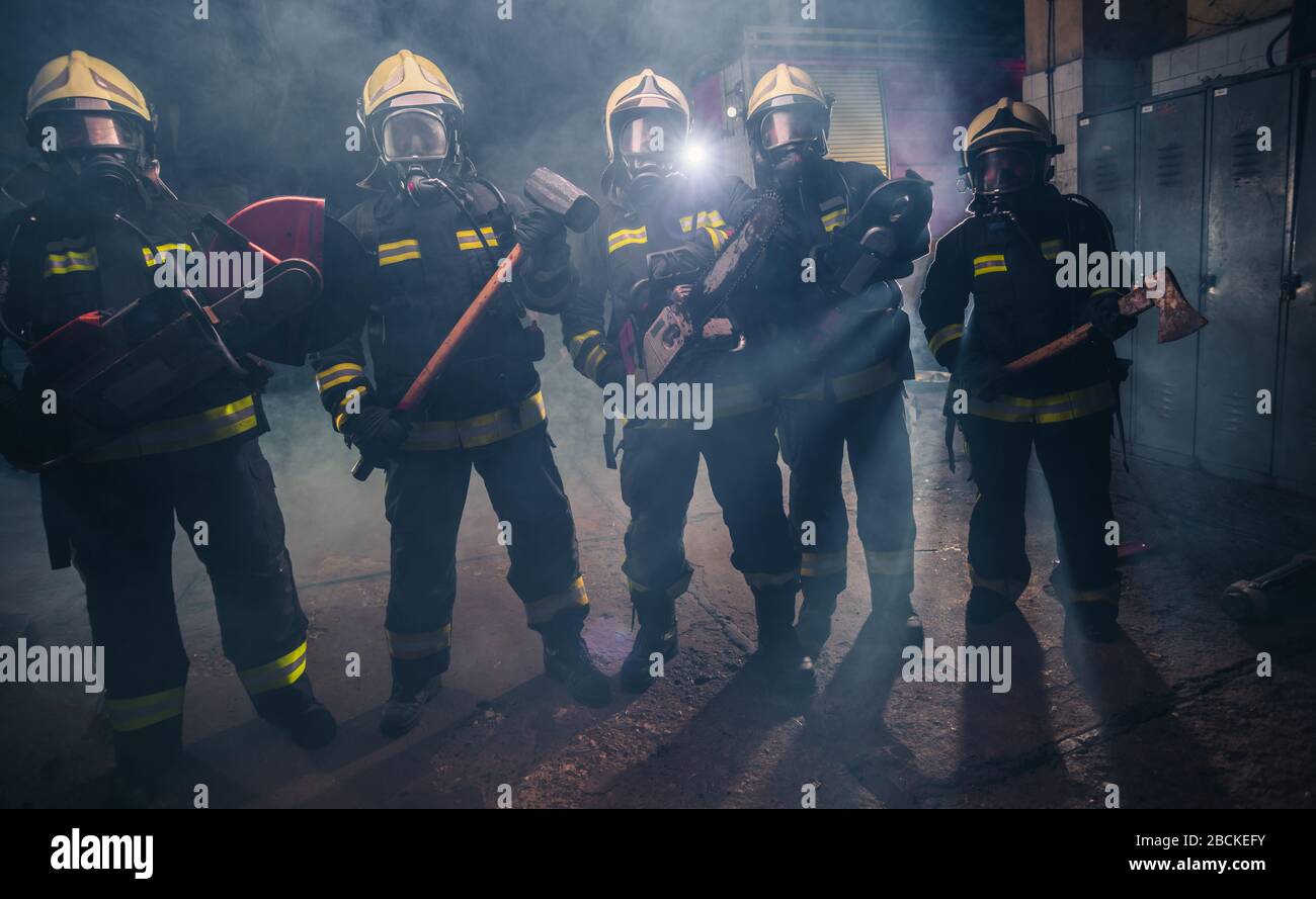 Group of firefighters with chainsaw and sledge hammer practicing in the ...