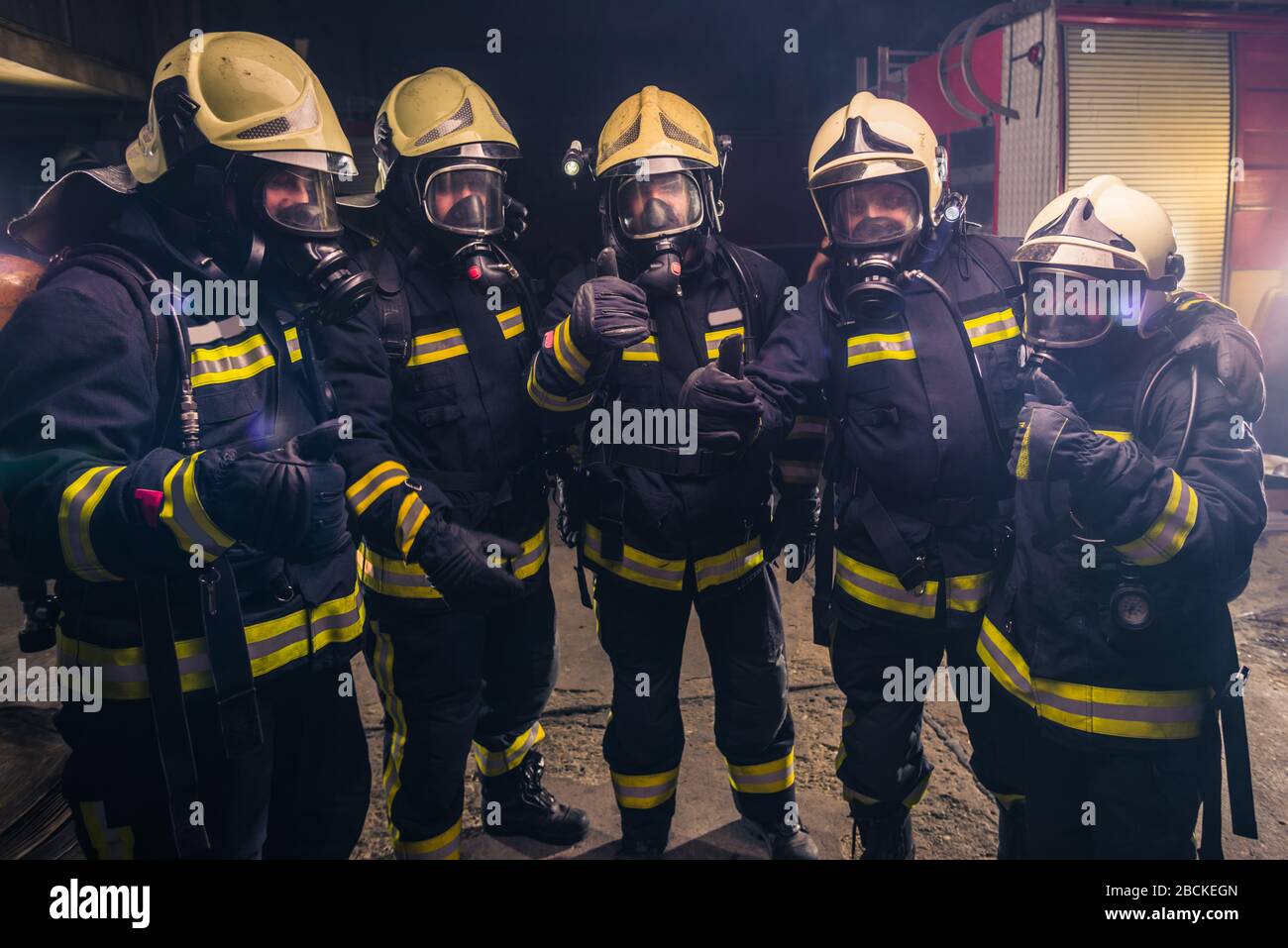 Team of firemen in uniform with gas masks inside the fire department ...