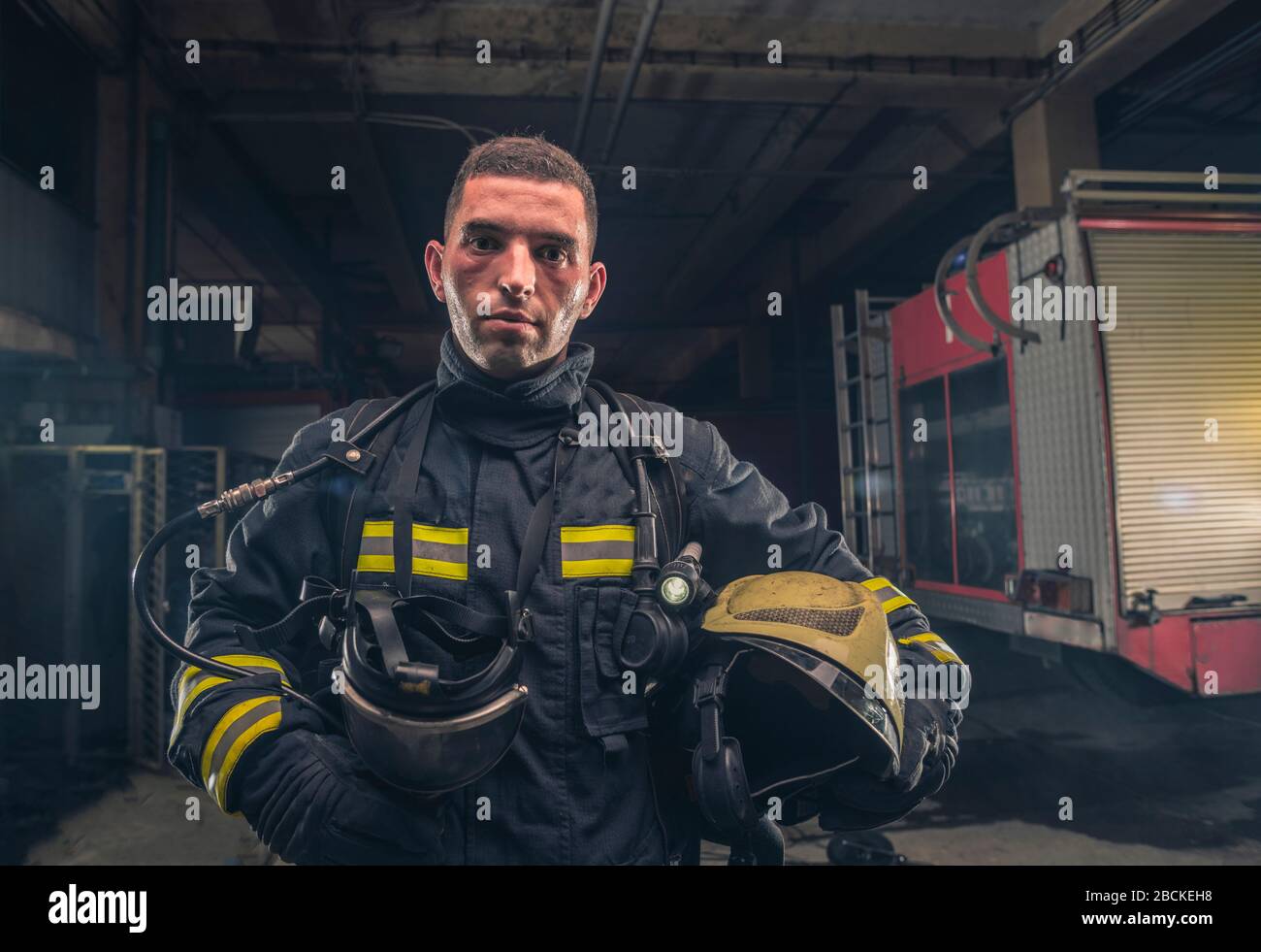 Portrait of a fireman wearing firefighter turnouts holding helmet ready ...