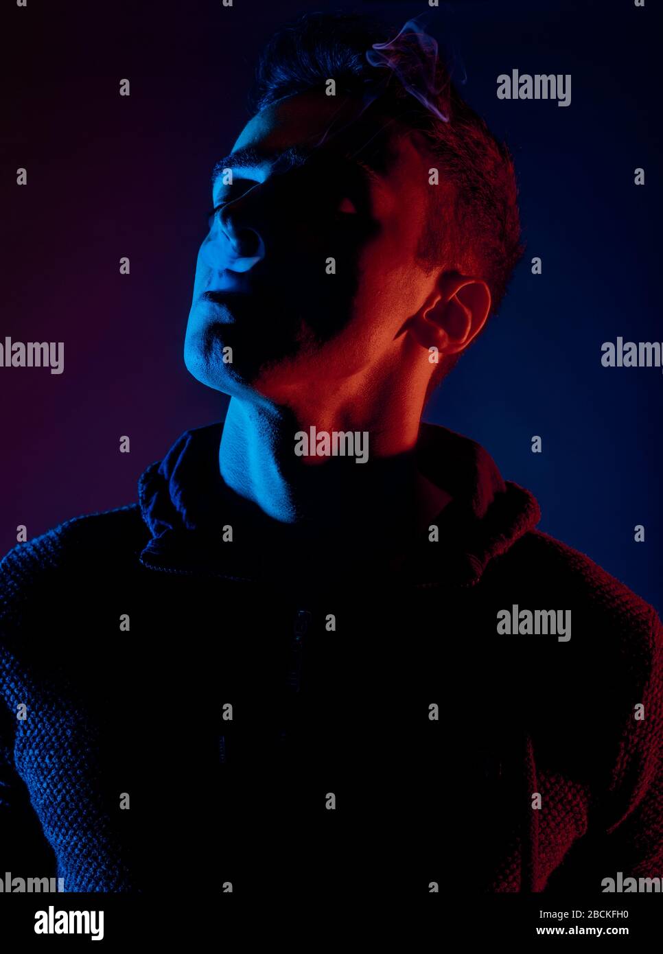 Studio body shot of an attractive man posing while smoke cigarette ...