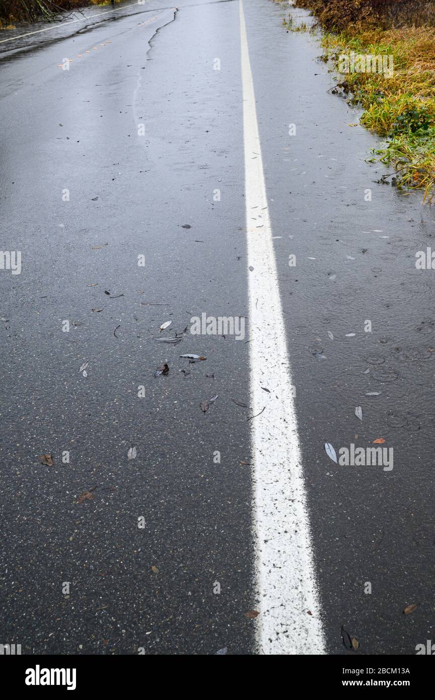 Residential street with water flooding over the roadway, still raining ...