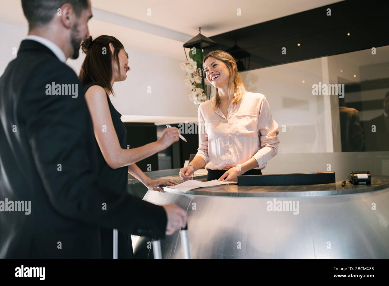 Portrait of two young business people check-in at hotel reception front ...